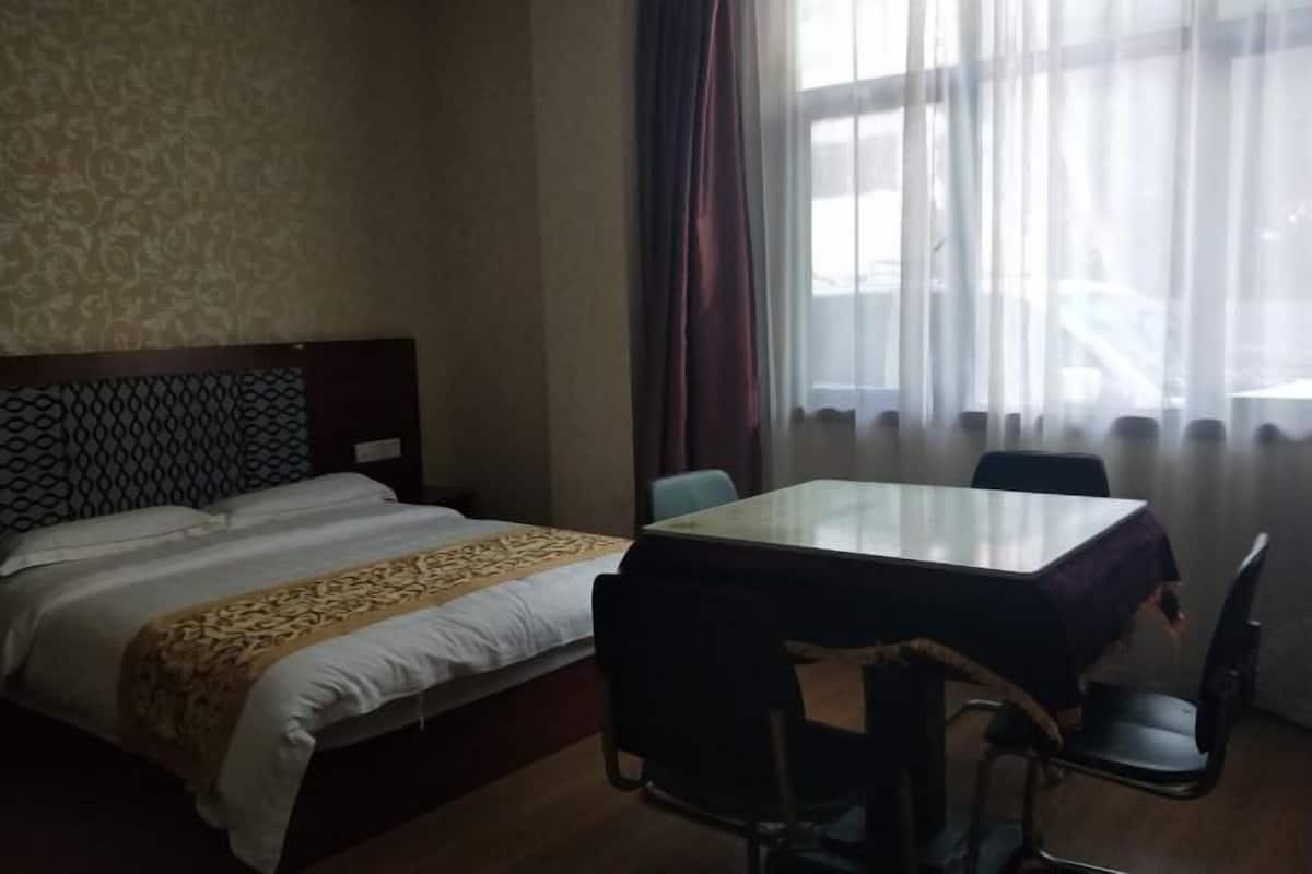 Quarto de hotel com cama, mesa e cadeiras.