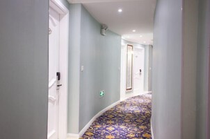 Um corredor com carpete estampado, paredes azul claras e uma porta branca.