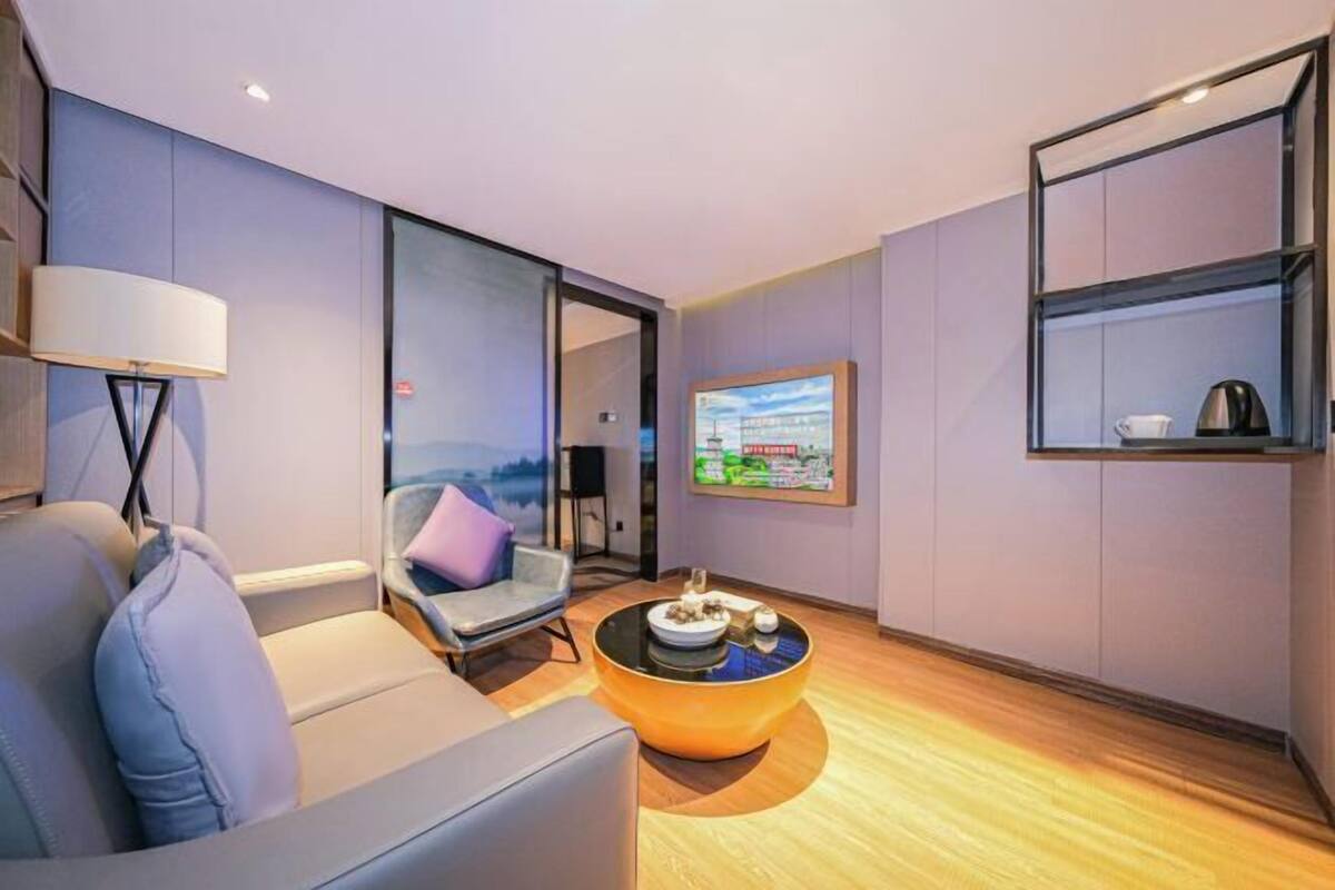 Quarto de hotel moderno com sofá, mesa de centro, televisão e vista para a água.