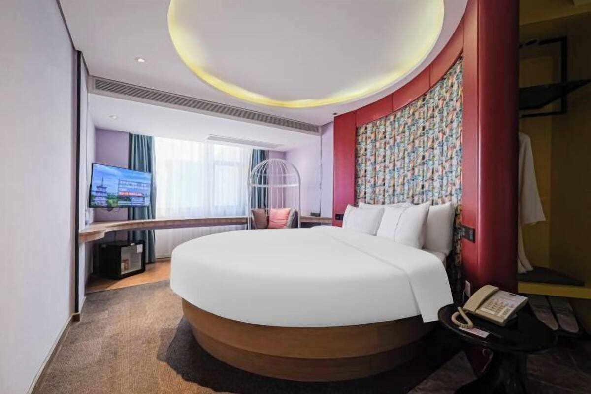 Quarto de hotel moderno com uma cama grande, uma televisão, uma mesa de escritório e um design de teto único.
