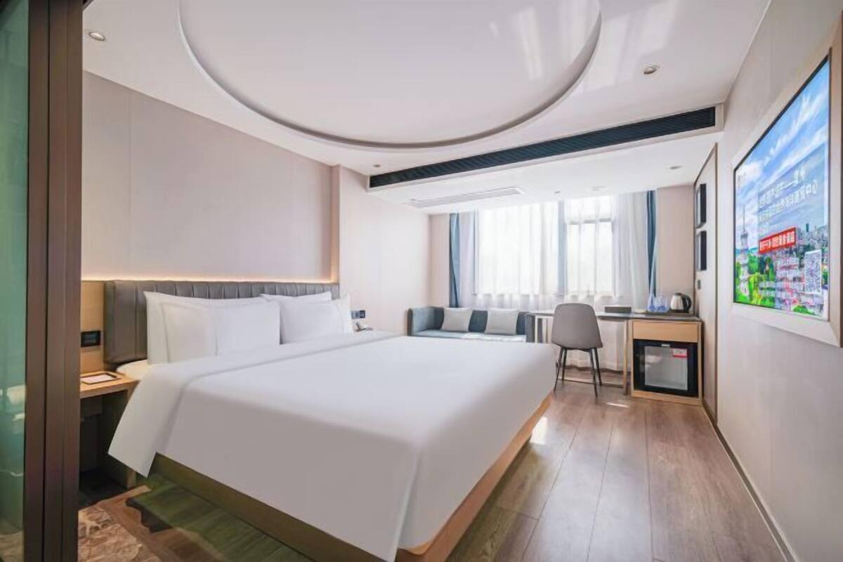 Quarto de hotel com uma cama grande, uma escrivaninha e uma cadeira.