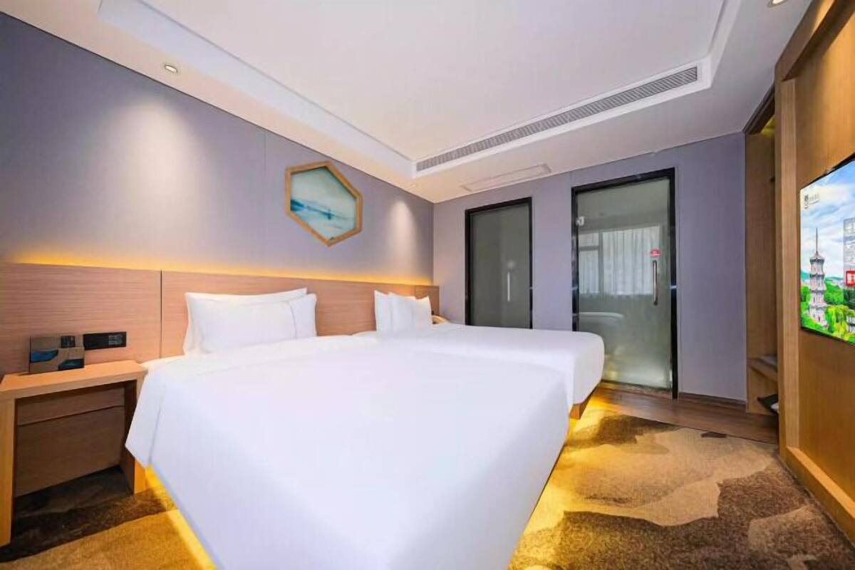 Quarto de hotel com uma cama grande, mesa de cabeceira, televisão e obra de arte na parede.