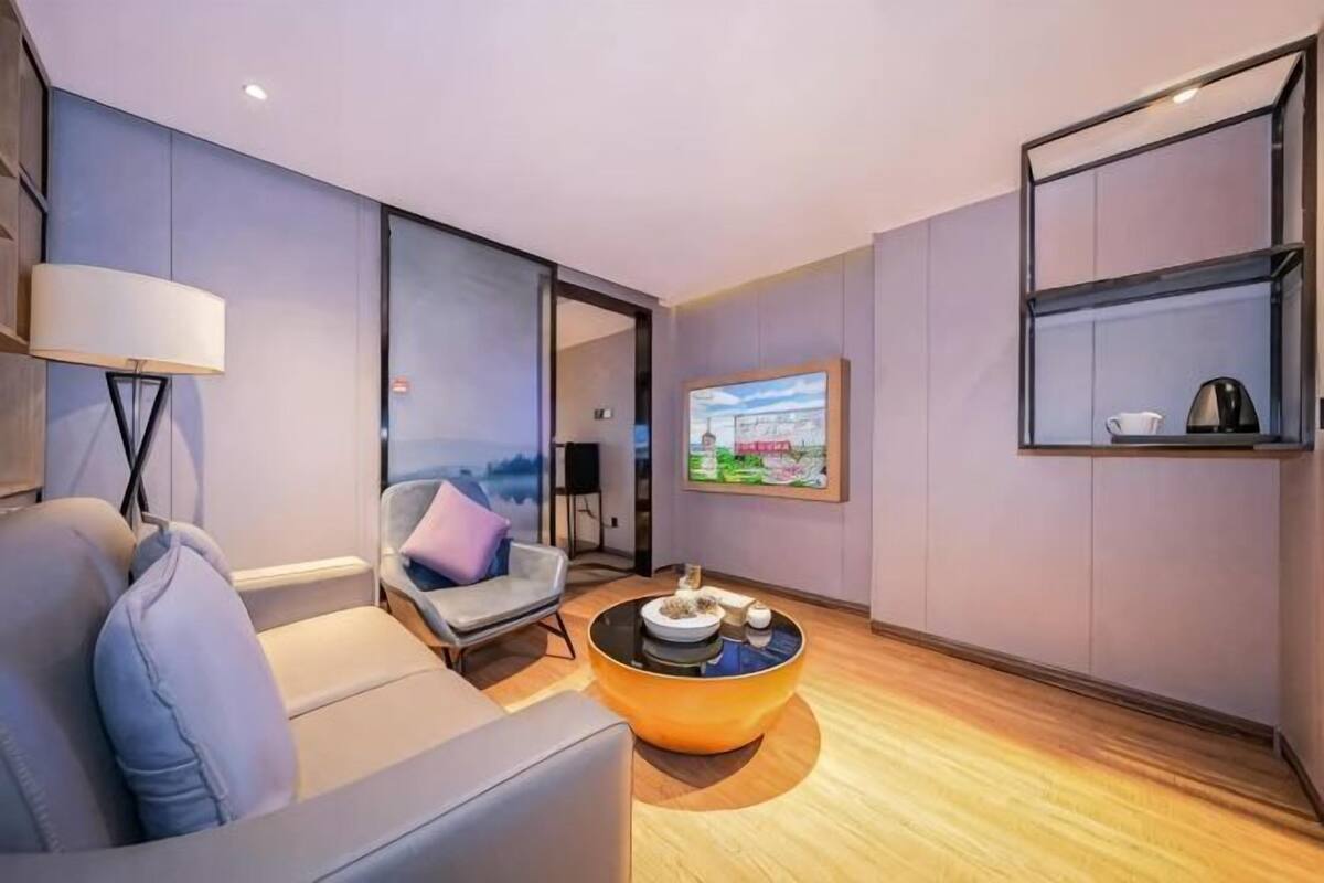 Uma sala de estar moderna com um sofá, uma mesa de centro, uma poltrona e um quadro na parede.