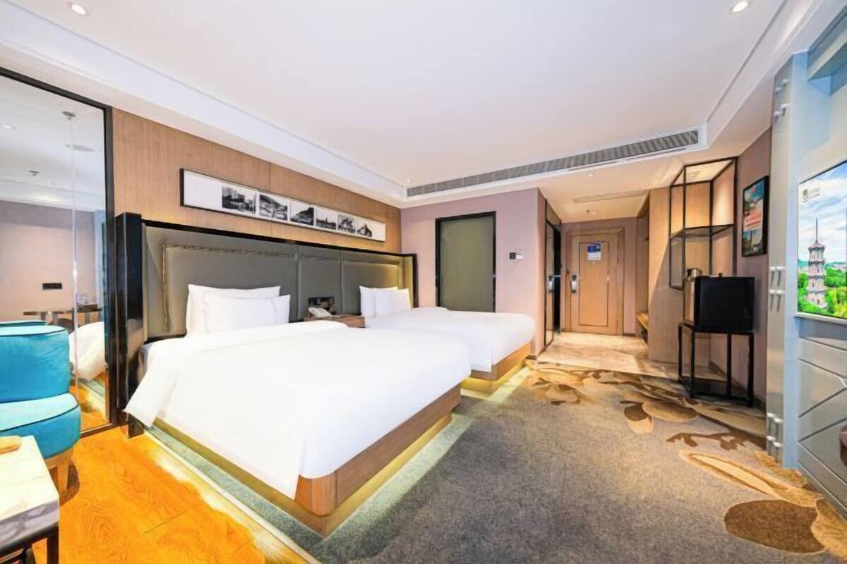 Quarto de hotel com uma cama grande, uma escrivaninha, uma cadeira e um guarda-roupa.
