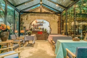 Um interior rústico com parede de tijolos, mobiliário de madeira e uma estrutura de vidro.