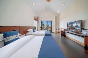 Quarto de hotel com duas camas, televisão e varanda com vista.