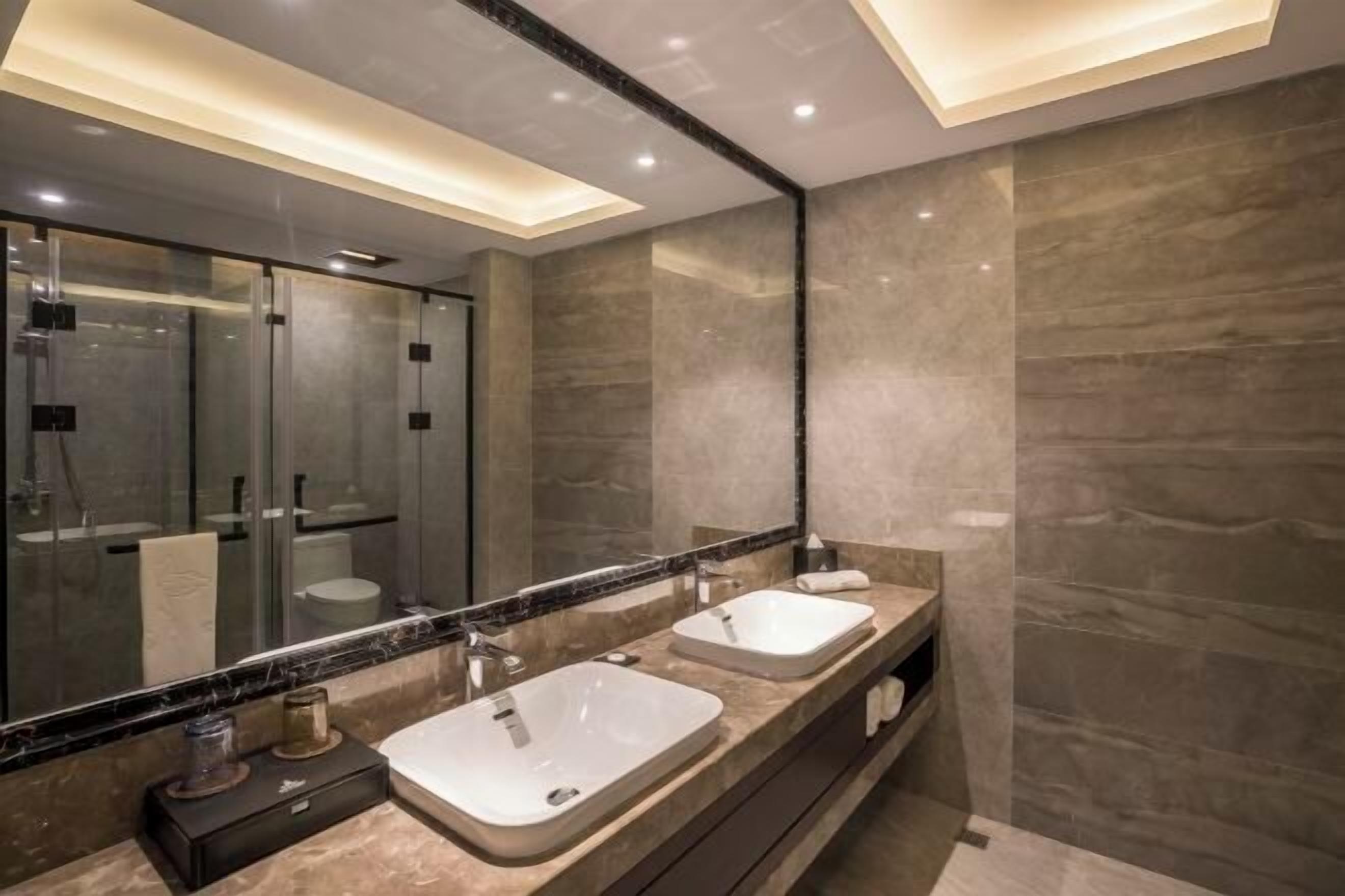 Casa de banho moderna com duas pias, um espelho grande e bancada de mármore.