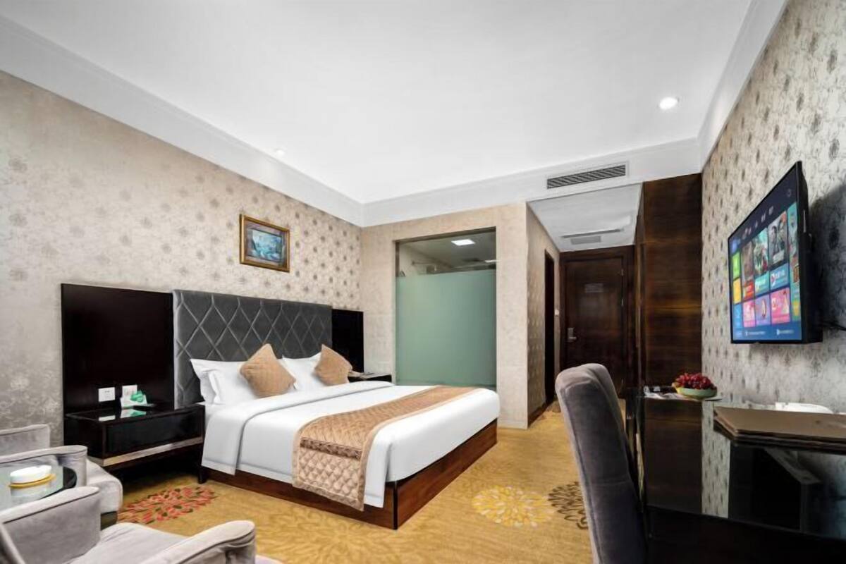 Quarto de hotel com cama, televisão, escrivaninha e cadeira.
