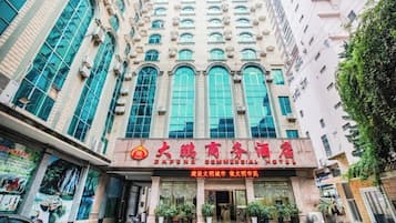 Um hotel com uma entrada ampla, várias janelas e uma placa com caracteres chineses.
