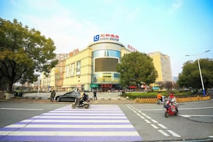 Um edifício com uma placa chamativa, uma faixa de pedestres e uma rua com veículos.