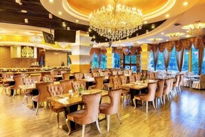 Um restaurante com várias mesas e cadeiras, um lustre e um espaço de bar.