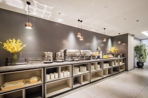 Uma bancada de café da manhã moderna com prateleiras de armazenamento, luminárias pendentes e um vaso com planta.