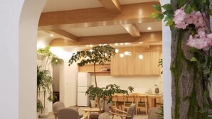 Uma sala de jantar moderna com mobiliário de madeira, plantas em vasos e uma árvore decorativa.