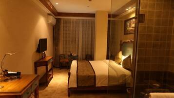 Quarto de hotel com cama, mesa de cabeceira, luminária e espelho.