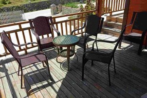 Um deck de madeira com móveis de exterior, incluindo cadeiras e uma mesa.
