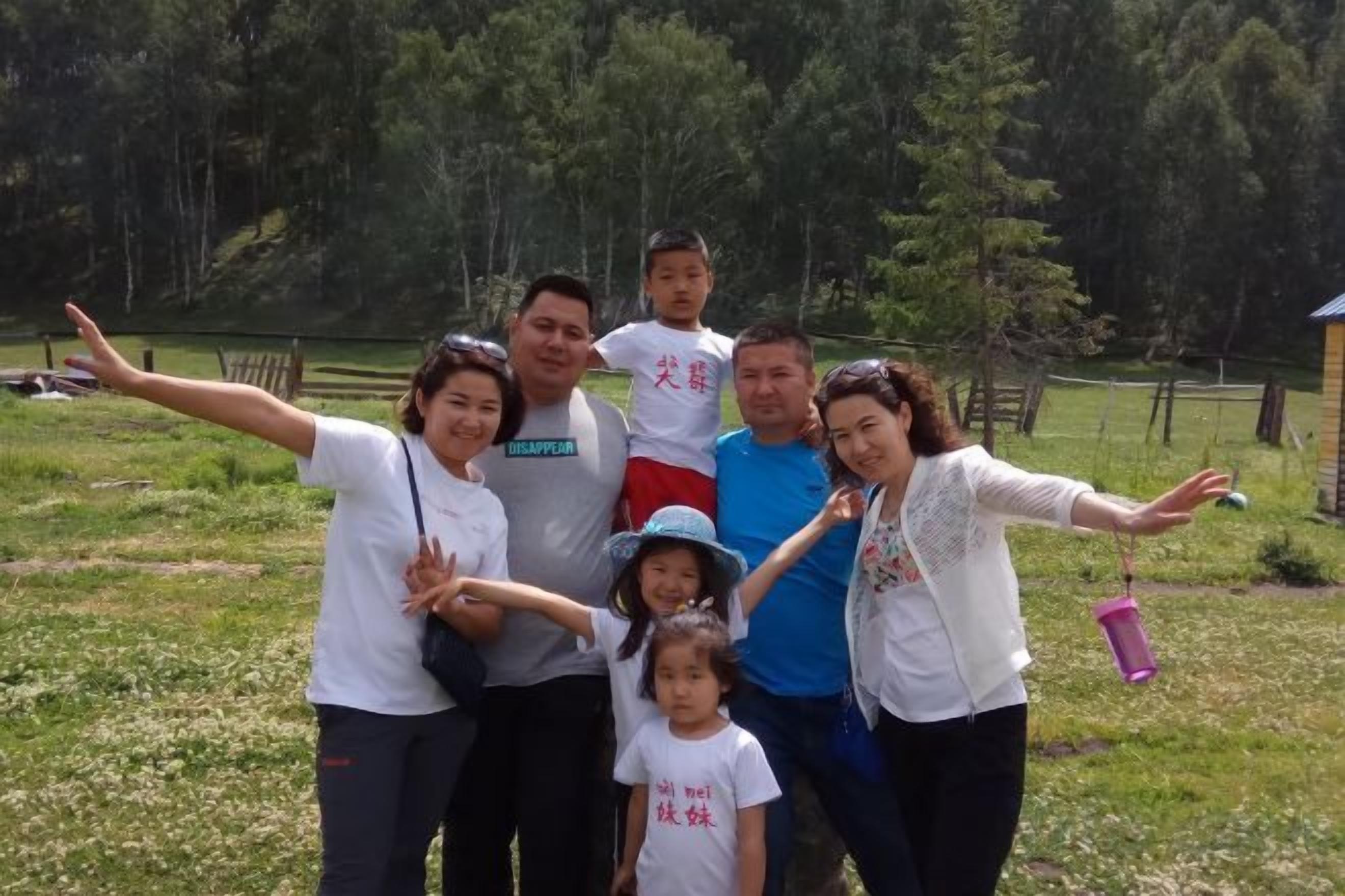 Um grupo de pessoas ao ar livre, com um campo gramado e árvores ao fundo.