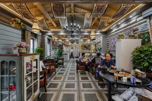 Um restaurante com chão estampado, teto de madeira e mesas com cadeiras.