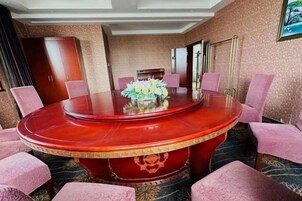 Sala de conferências com mesa redonda, cadeiras e um arranjo floral.