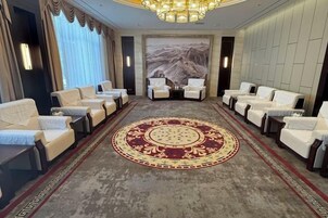 Sala de reuniões com piso carpete, uma pintura grande e várias cadeiras dispostas para uma reunião.