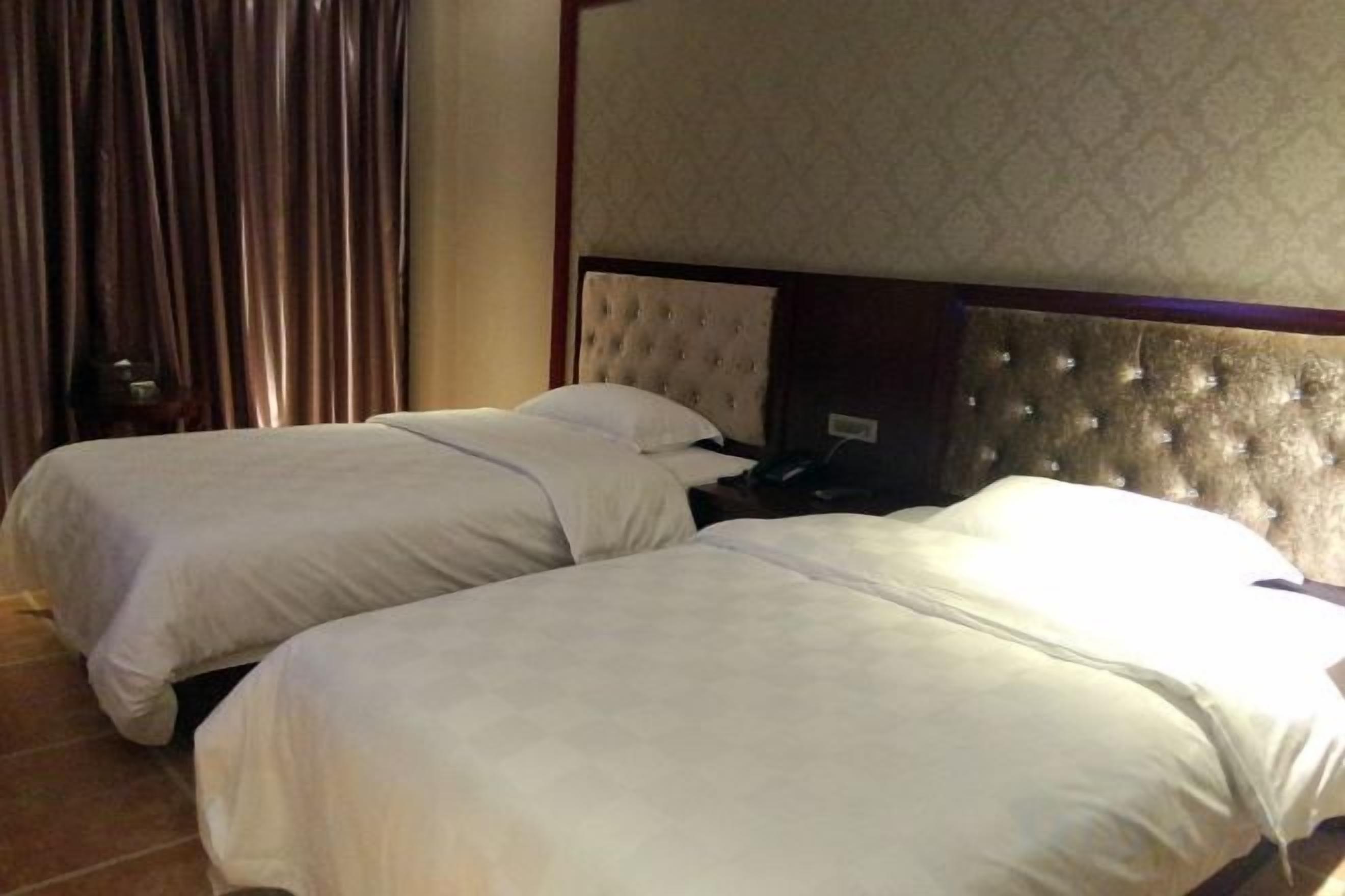 Quarto de hotel com duas camas, cabeceira e cortina.
