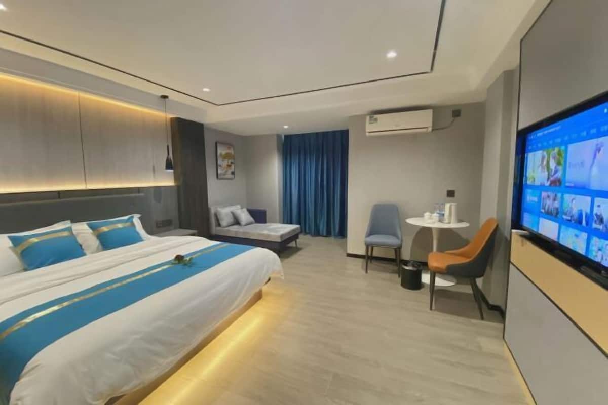 Quarto de hotel com cama, escrivaninha, cadeira, televisão e ar condicionado.