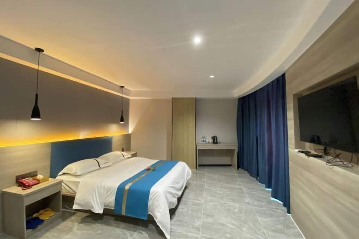 Quarto de hotel com uma cama, mesa de cabeceira e televisão.