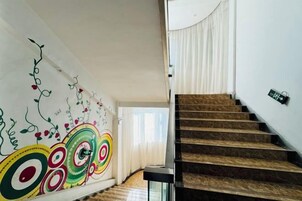 Uma escada de design moderno conduz a um quarto com uma grande pintura abstrata na parede.