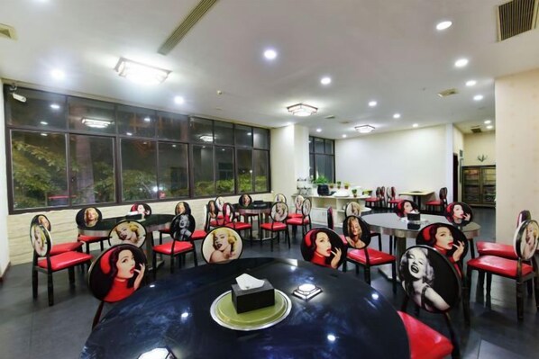 Sala de conferência com mesas redondas, cadeiras e uma grande janela com vista para árvores.