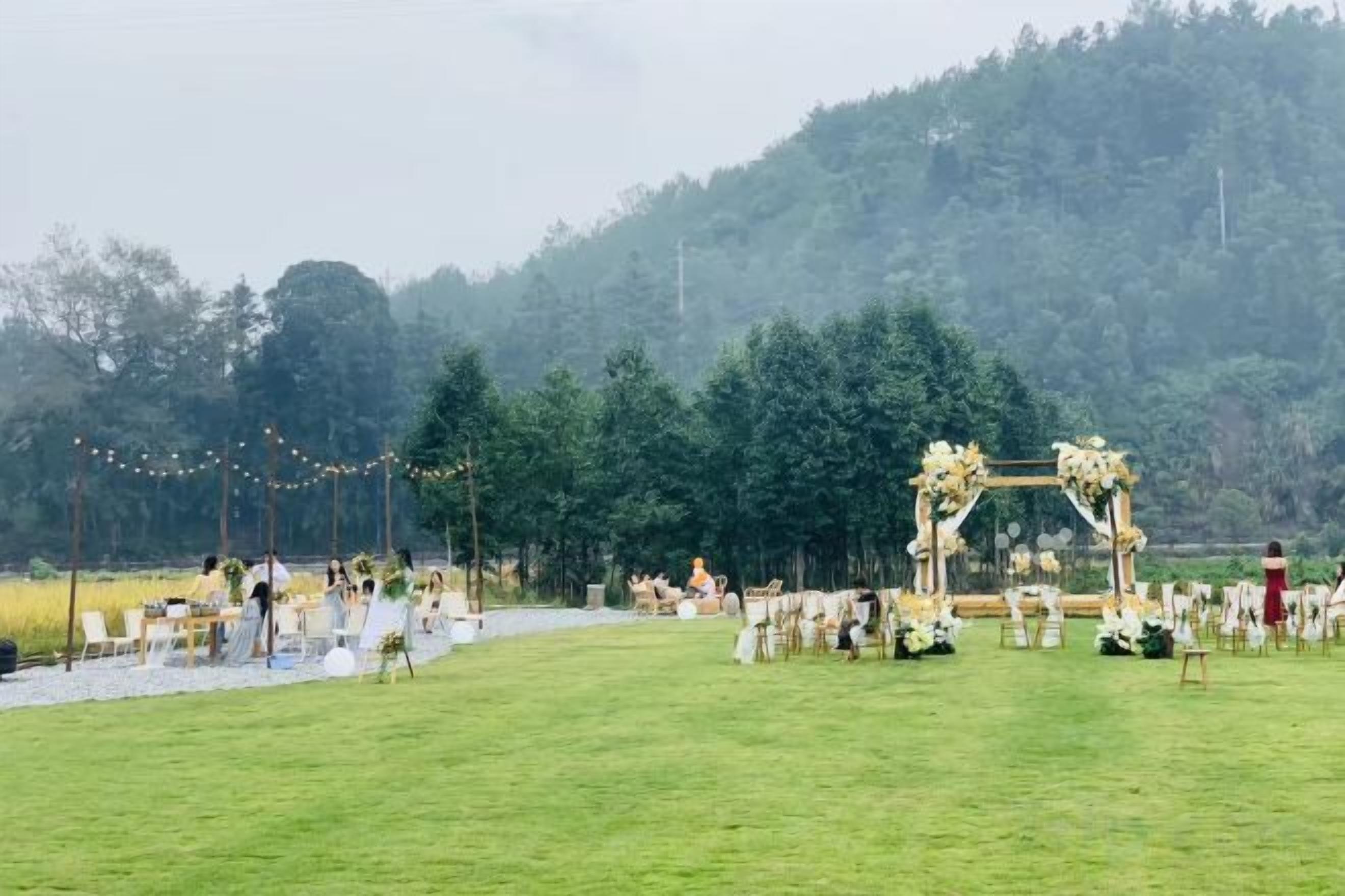 Espaço para casamento ao ar livre com área gramada, disposição de assentos e um arco decorativo.