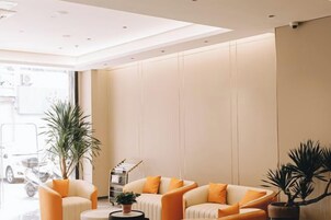 Um saguão moderno de hotel com área de estar, balcão de recepção e uma grande janela.