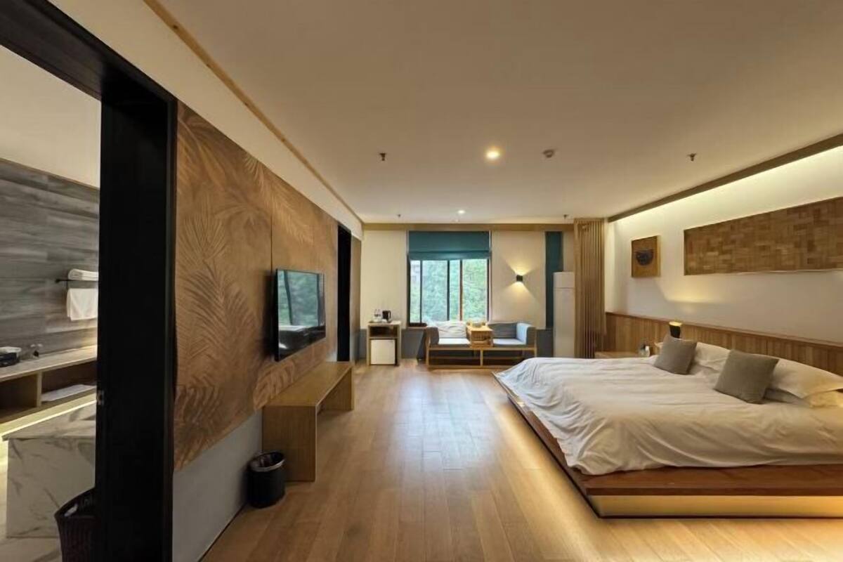Quarto moderno com uma cama grande, uma escrivaninha e um espaço de estar.