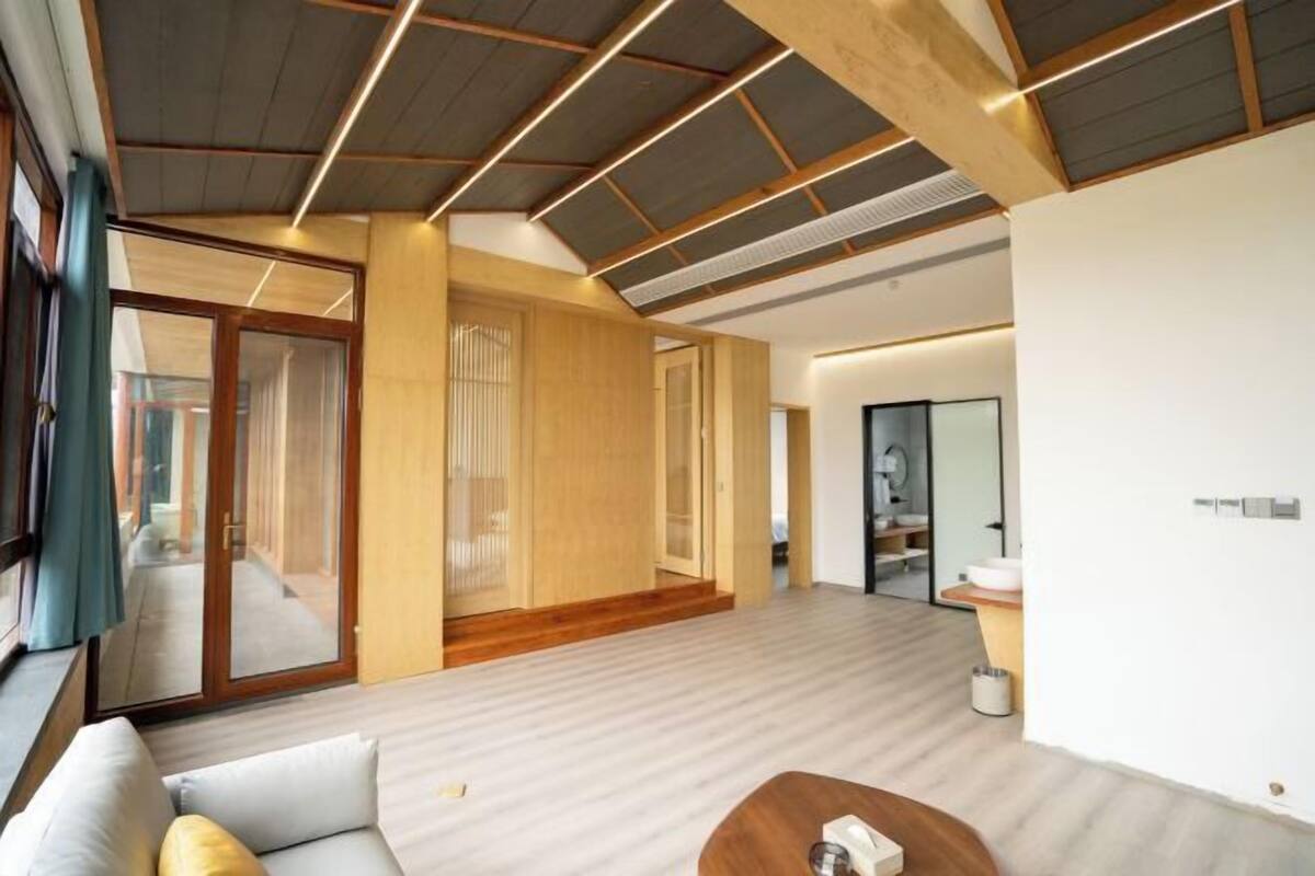 Interior moderno com teto de madeira, um sofá, uma mesa de centro e uma porta de vidro deslizante que dá para uma varanda.