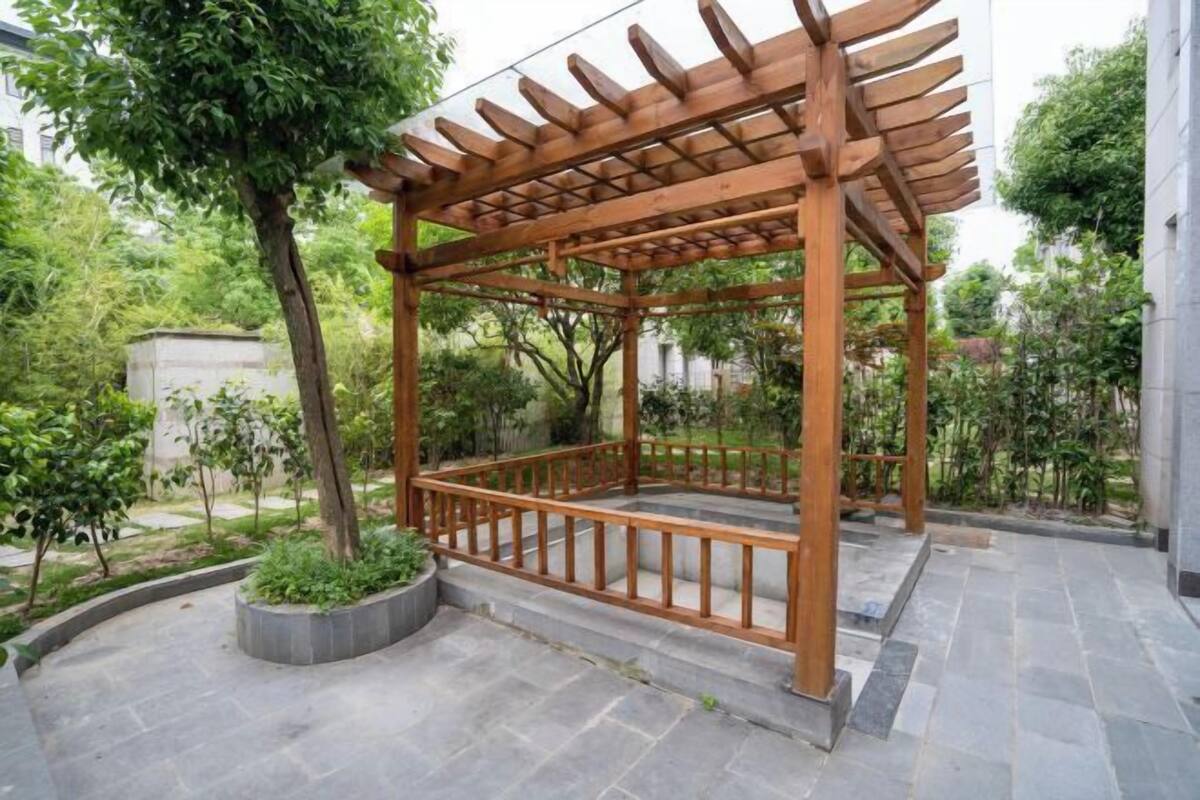 Uma estrutura de pérgola de madeira com um pátio de tijolos de pedra.