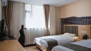 Quarto de hotel com duas camas, uma escrivaninha, uma cadeira e uma janela grande com cortinas.