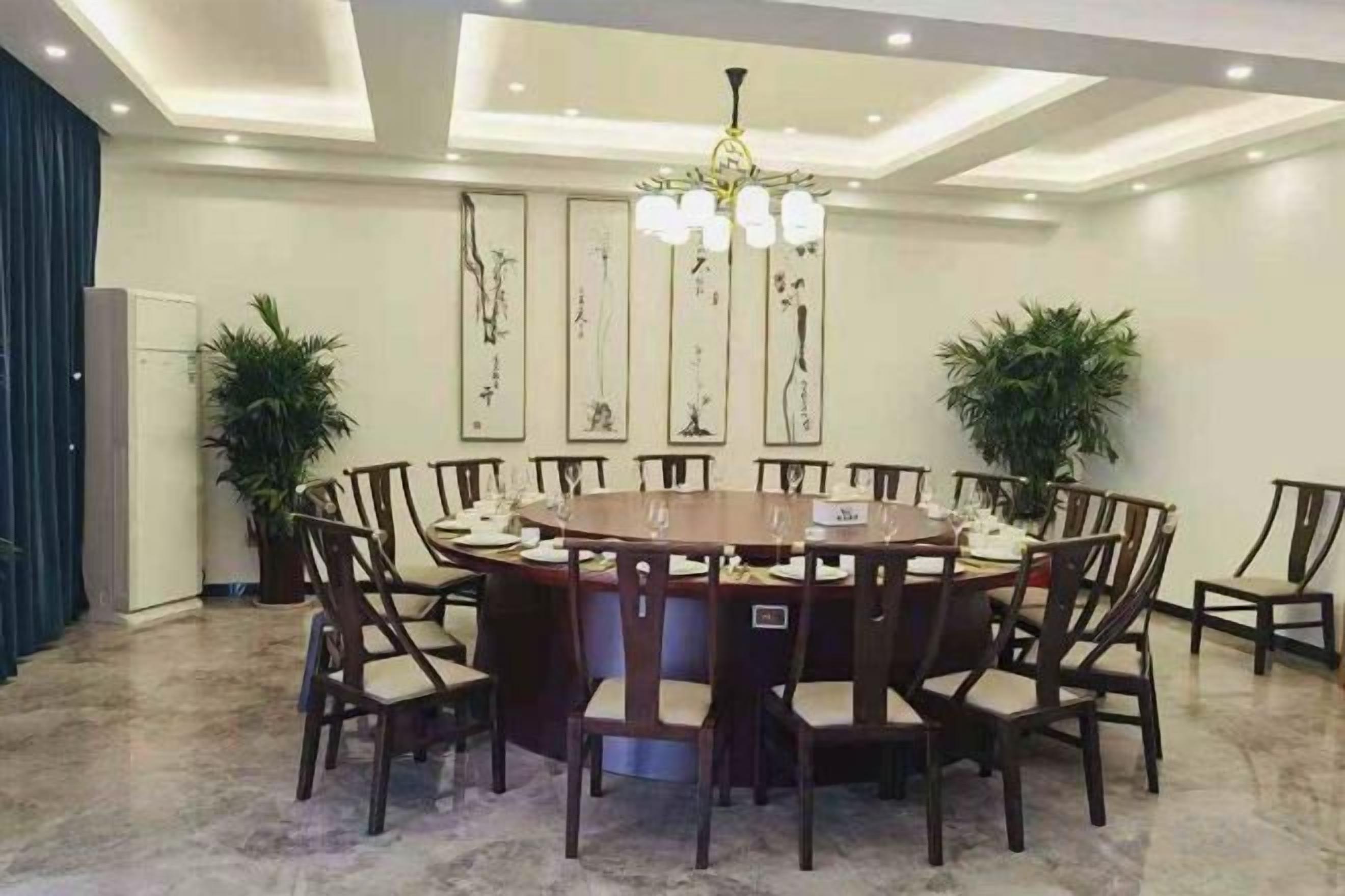 Sala de conferências com mesa redonda, cadeiras e lustre.