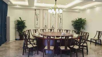 Sala de conferências com mesa redonda, cadeiras e lustre.