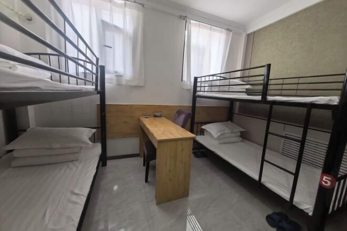 Quarto em dormitório com beliches, escrivaninha e cadeira.