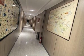 Um corredor com um mapa na parede, um extintor de incêndio e uma lixeira.