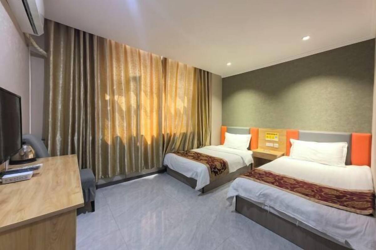 Quarto de hotel com duas camas, uma escrivaninha e uma televisão.