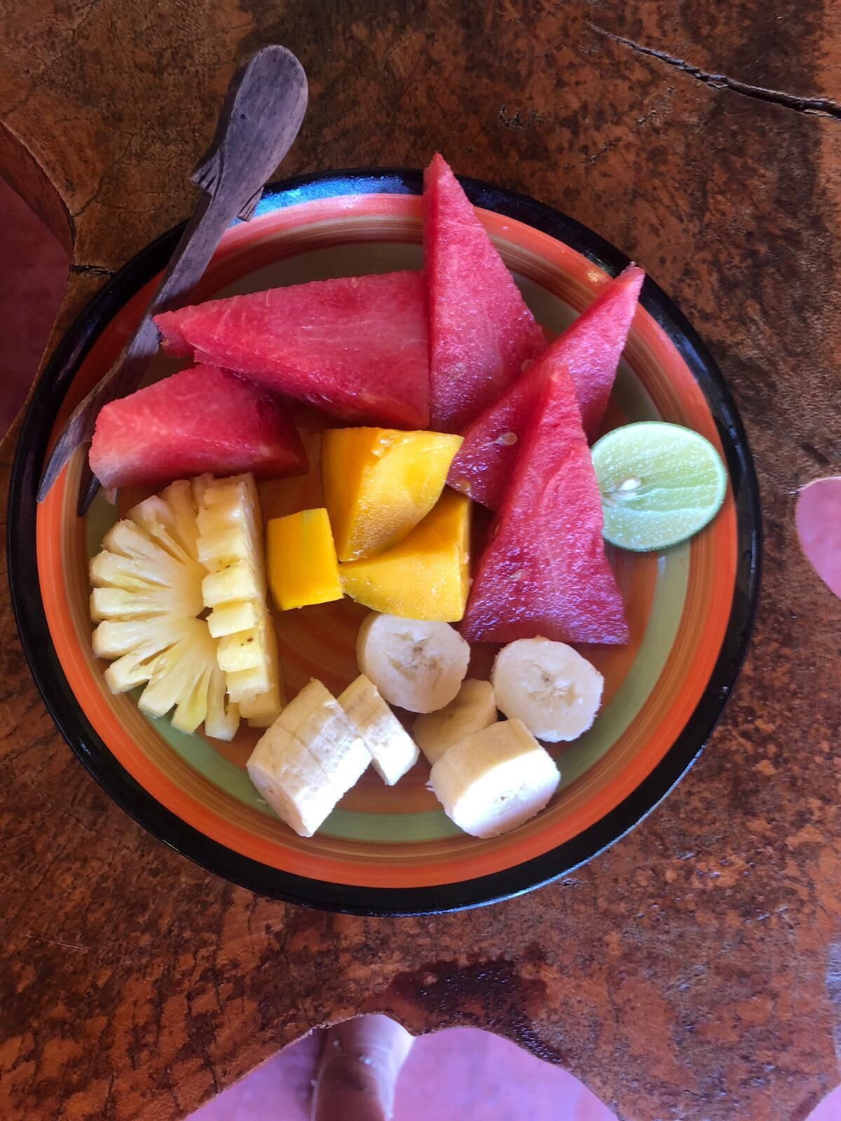 Uma tigela com frutas, incluindo melancia, abacaxi, banana e fatias de manga.