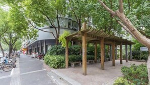 Rua arborizada com uma galeria coberta e bancos.