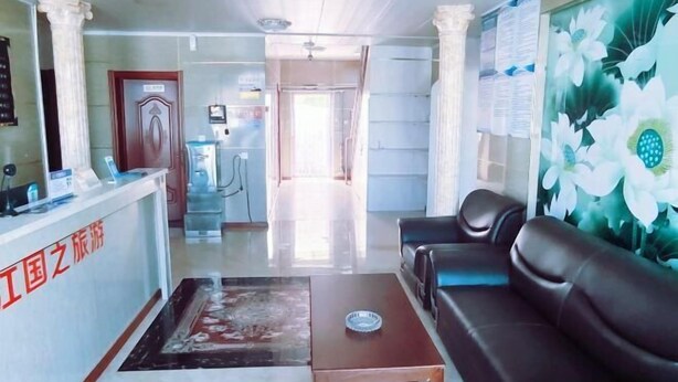 Uma área de recepção com balcão, um sofá, uma mesa de centro e uma parede com um mural floral.