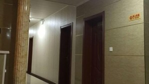 Um corredor com colunas de mármore, portas de madeira e uma placa na parede.