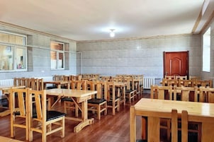 Um quarto com várias mesas e cadeiras de madeira dispostas para refeições.