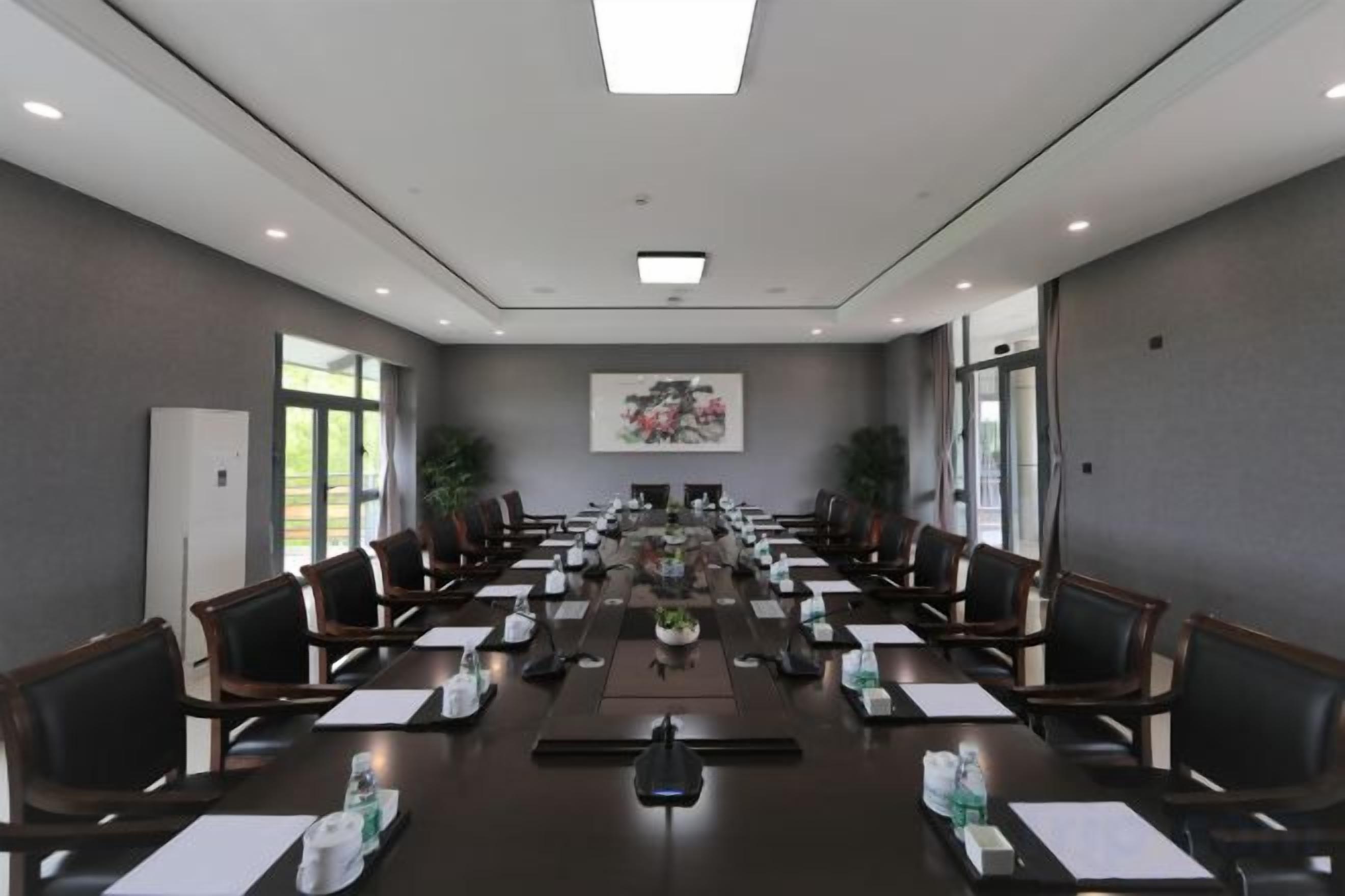 Uma sala de conferência com uma mesa comprida, cadeiras e um projetor.