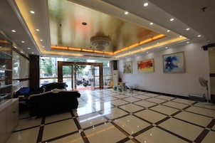 Um saguão de hotel com balcão de check-in, área de estar e obras de arte nas paredes.