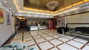Um saguão de hotel com balcão de recepção, área de estar e um candelabro.