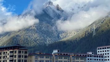 Um hotel com vários andares, paisagem montanhosa ao fundo e céu claro.