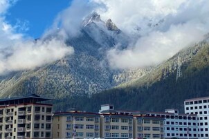 Um hotel com vários andares, paisagem montanhosa ao fundo e céu claro.