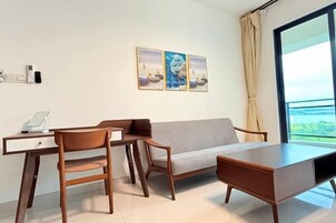 Quarto moderno com escrivaninha, duas cadeiras, um sofá e uma janela grande com vista.